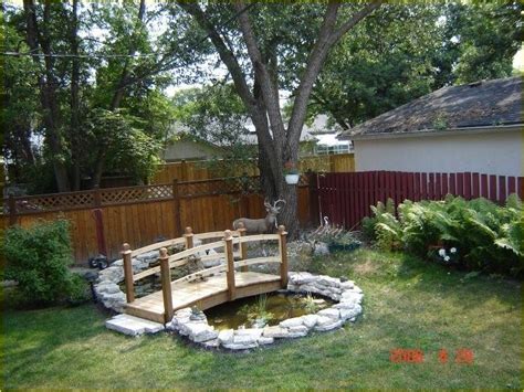 A Wooden Bridge Over A Small Pond In A Yard