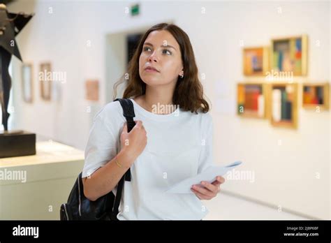 Focused Girl Visitor Examines An Exhibit In An Art Gallery Stock Photo