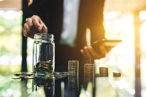 Premium Photo Closeup Of A Businesswoman Putting Coins In A Glass Jar