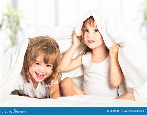 Les Petites Filles Heureuses Jumelle La Soeur Dans Le Lit Sous Avoir