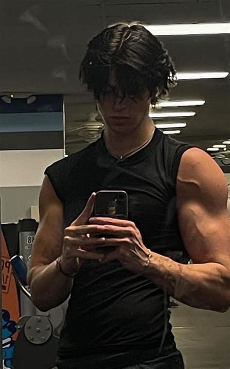 A Man Standing In A Gym Looking At His Cell Phone