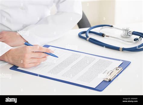 Female Doctor Hands Writing On Sheet In A Clipboard With A Pen Stock