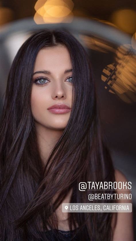 A Woman With Long Dark Hair And Blue Eyes Posing For A Photo In Front