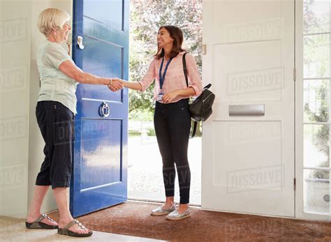 Senior Woman Greeting Female Care Worker Making Home Visit Stock