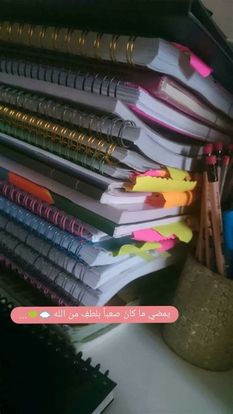 A Pile Of Papers And Pens Sitting On Top Of A Desk Next To A Vase