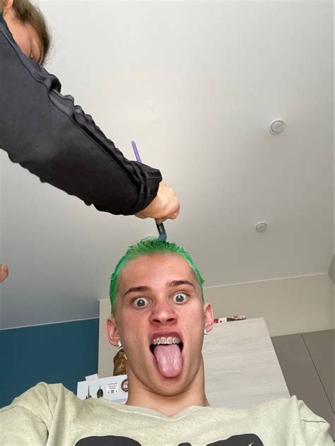 A Man With Green Hair Is Getting His Hair Cut By Another Person In The
