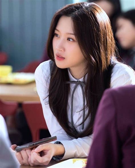 A Woman Sitting At A Table With A Cell Phone In Her Hand And Another