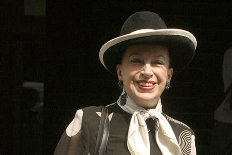Geneviève de Fontenay en chapeau bicolore et chemise noire imprimée de