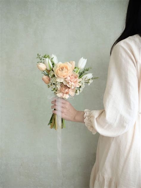 A Woman Holding A Bouquet Of Flowers In Her Hand