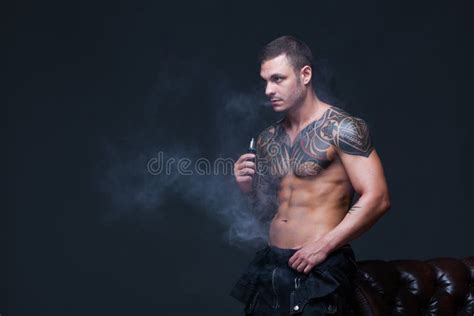 The Man With A Muscular Naked Torso With Tattoos On The Dark Background
