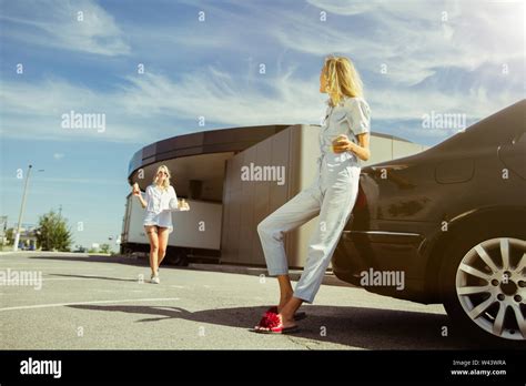 Young Lesbians Couple Preparing For Vacation Trip On The Car In Sunny Day Shopping And