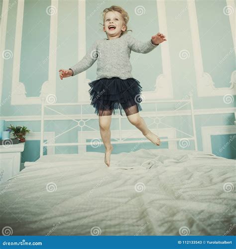 Vieille Fille De Cinq Ans Heureuse Sautant Sur Le Lit Image Stock