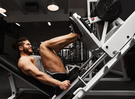Hombre Atlético Del Levantamiento De Pesas En Pierna Del Gimnasio