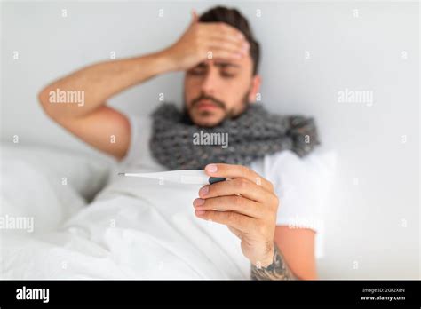Sick Man Checking Body Temperature Holding Thermometer And Touching