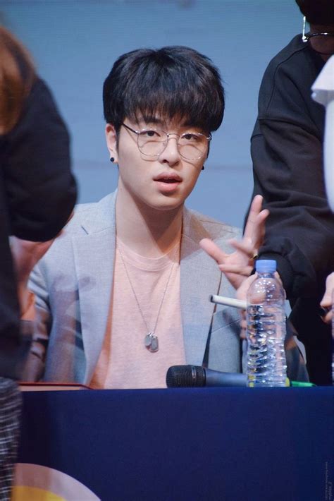 A Man In Glasses Sitting At A Table With A Water Bottle On His Lap And