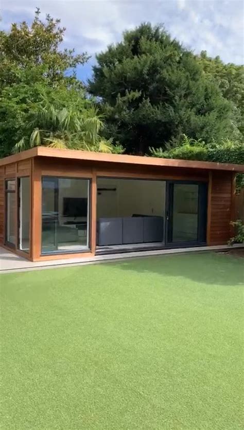 A Small Wooden Building Sitting On Top Of A Lush Green Field