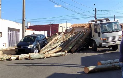 Caminhão toras de madeira derruba carga e interdita rua em