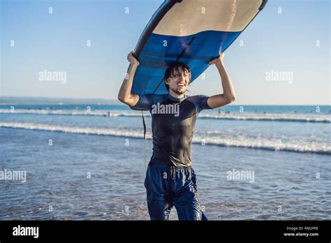 Man Carrying Surfboard Over His Head Close Up Of Handsome Guy With