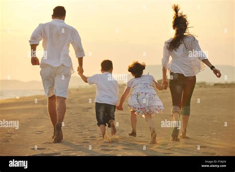 glückliche junge Familie viel Spaß am Strand laufen und springen bei