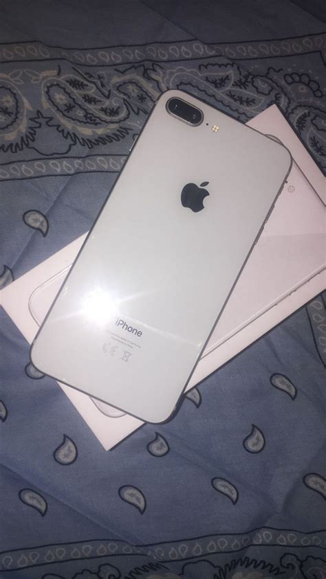 Two Iphones Sitting On Top Of Each Other On A Blue And White Bed Spread