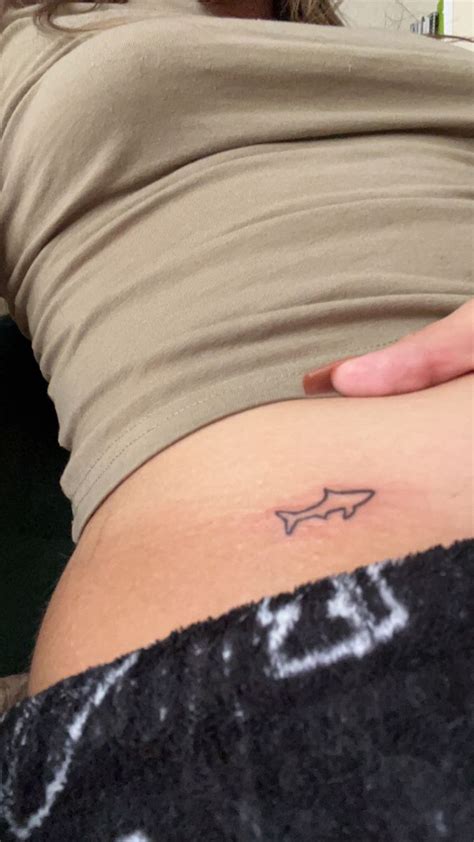 A Woman With A Small Tattoo On Her Stomach Is Sitting Down And Looking