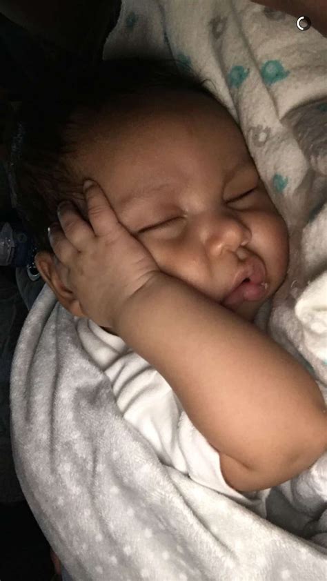 A Baby Is Sleeping On A Blanket With Its Head Resting On The Arm Of