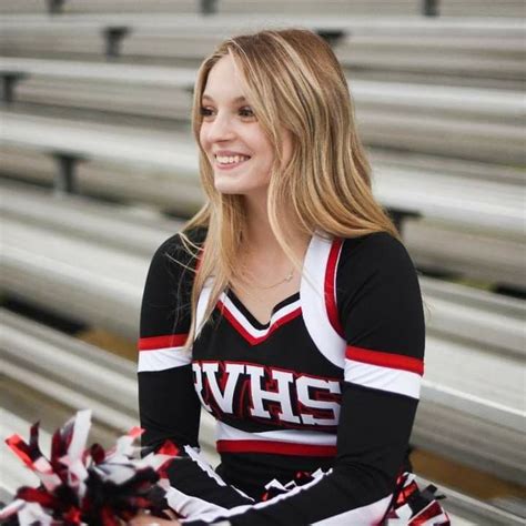 A Cheerleader Sitting On The Bleachers With Her Pom Poms