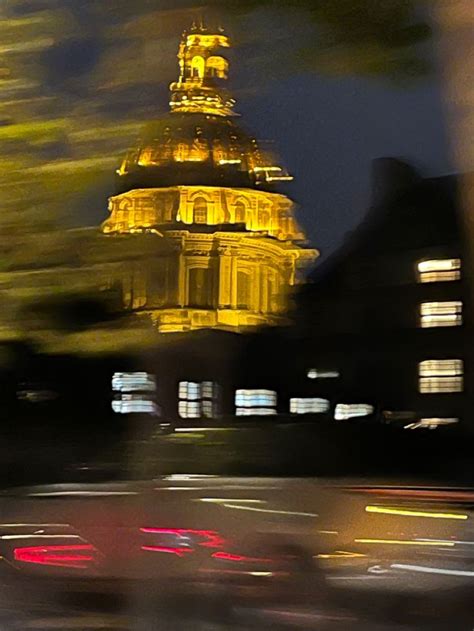 A Blurry Photo Of A Building With A Clock Tower In The Background At Night