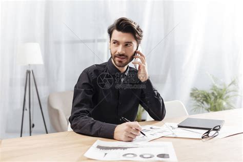 一位留着深色头发和胡须的年轻人坐在办公室的桌子旁高清图片下载 正版图片502952222 摄图网