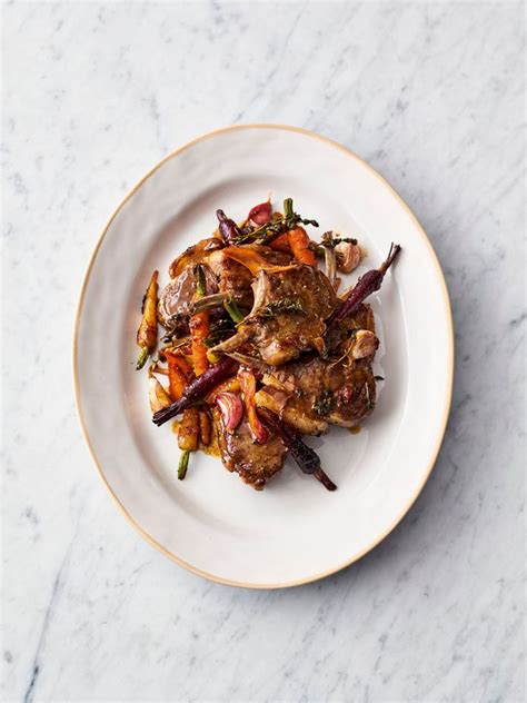 A White Plate Topped With Meat And Veggies On Top Of A Marble Counter