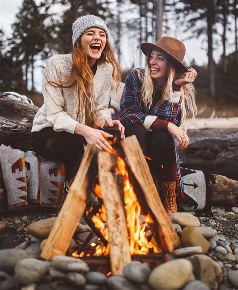 Two Women Sitting Around A Campfire Laughing