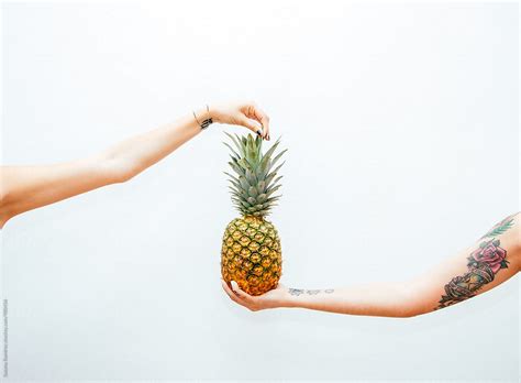 Two Arms Holding A Pineapple by Stocksy Contributor Susana Ramírez
