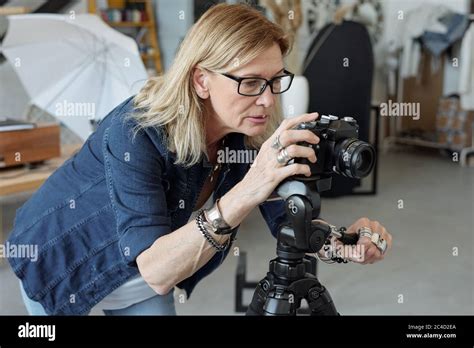 Concentrated Mature Photographer In Eyeglasses Looking Through Camera