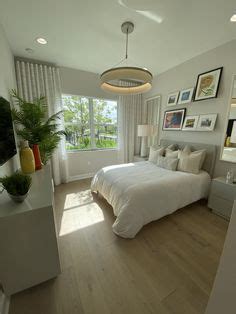 A Bedroom With White Walls And Wood Flooring Has A Large Bed In The Corner