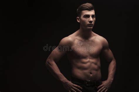 El Doblar Masculino Joven En Fondo Oscuro Del Estudio Con Las Manos En