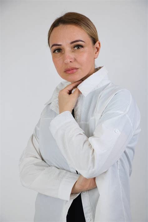 Mulher Loira De Camisa Branca A Posar Perto De Um Fundo Branco Imagem