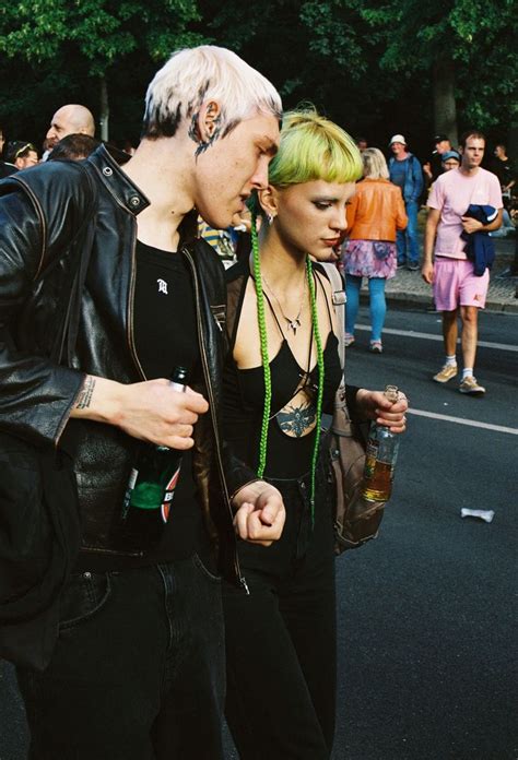 Two People Standing Next To Each Other On A Street With Lots Of People