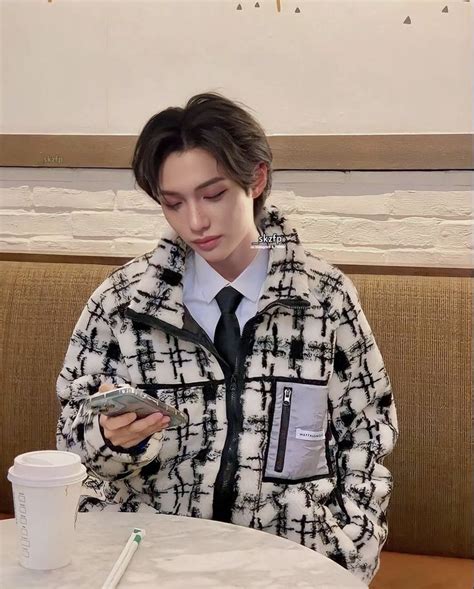 A Person Sitting At A Table With A Cell Phone In Their Hand And A Cup