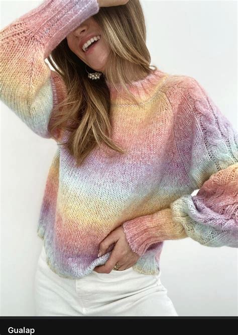 A Woman Wearing A Colorful Sweater And White Pants Posing With Her