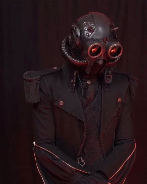 A Man In A Black Suit With Red Eyes And A Gas Mask On His Face
