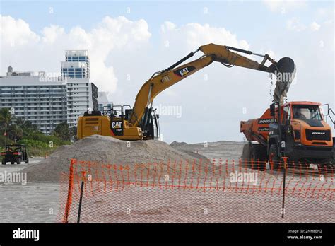 Ein Bagger befindet sich auf einem großen Haufen Sandstrand und lädt