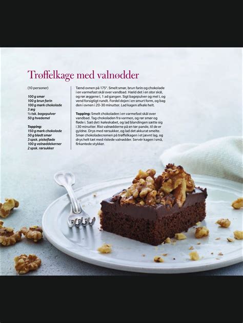 A Piece Of Chocolate Cake On A Plate With Walnuts Around It And A Fork