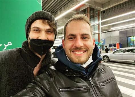 Two Men Standing Next To Each Other Wearing Masks
