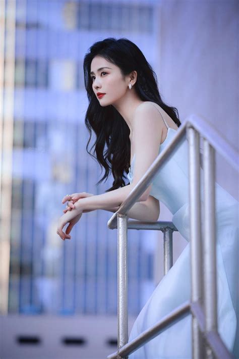 A Woman Sitting On Top Of A Metal Hand Rail Next To A Building And