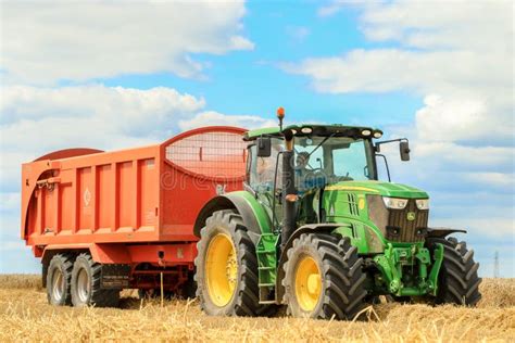 A Modern Green Tractor Stands Directly Next To The Combine And