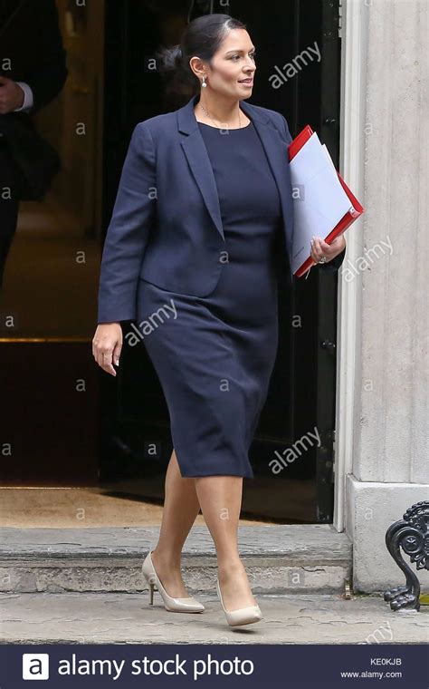A Woman In A Blue Dress And Heels Is Walking Out Of The Door With Her Folder