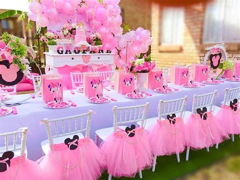 A Table Set Up For A Minnie Mouse Birthday Party With Pink And Black
