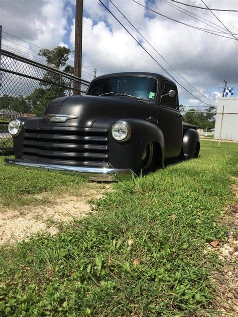 An Old Black Truck Is Parked In The Grass