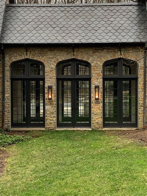 A Brick House With Double Doors And Windows On The Front Side