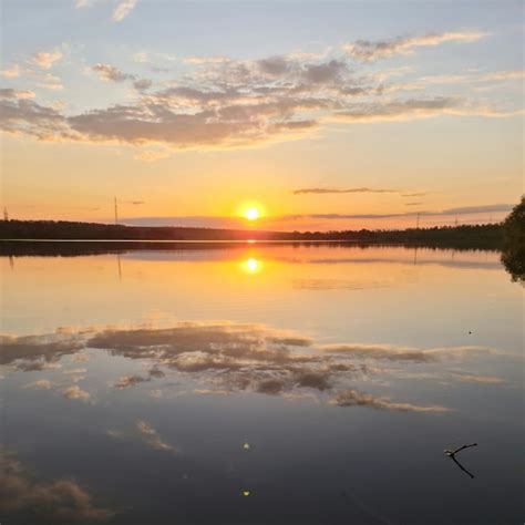 Un Lago Con Una Puesta De Sol Y Un Reflejo Del Cielo Y Las Nubes